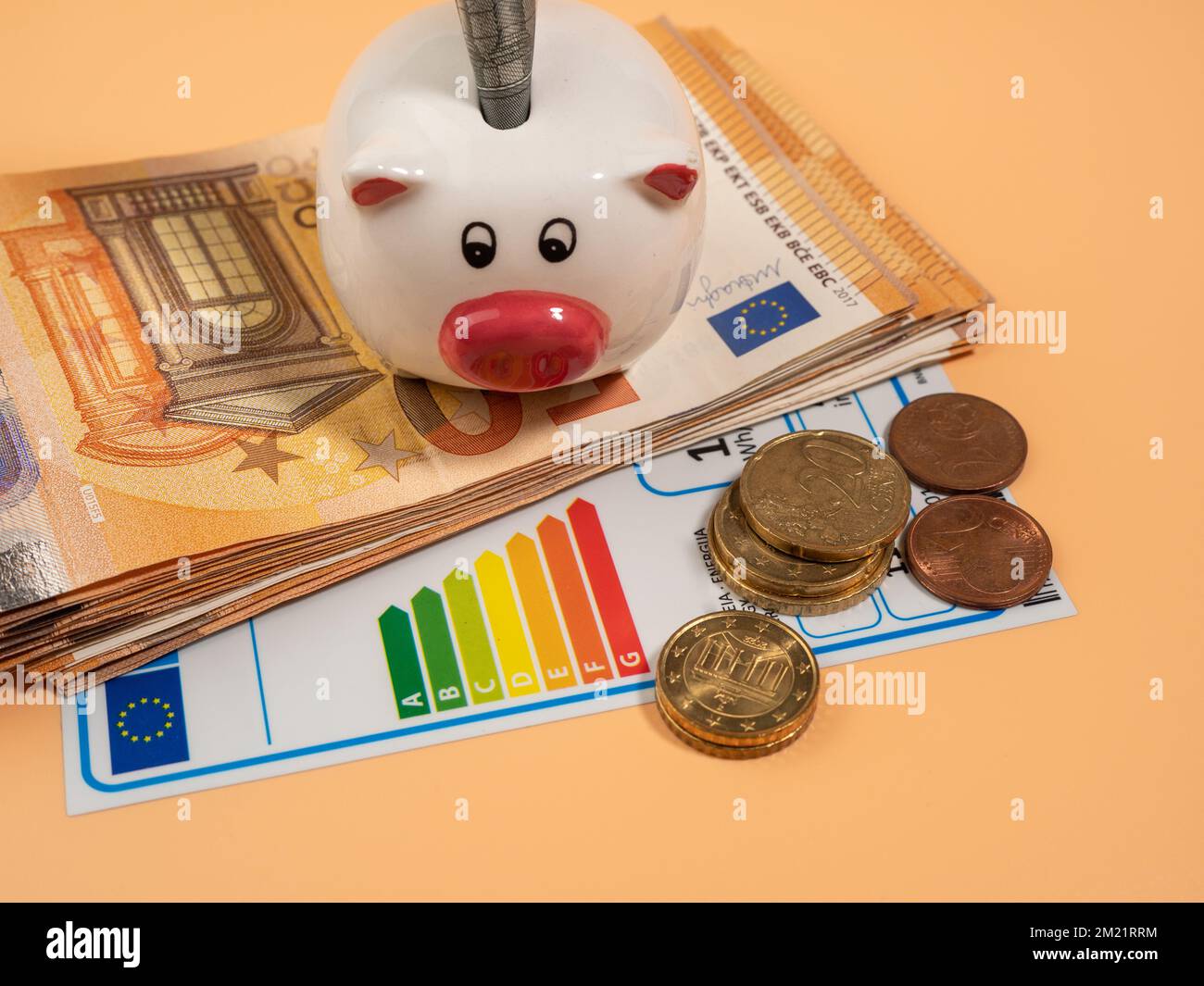Money, piggy bank and energy efficiency certificate on orange ...