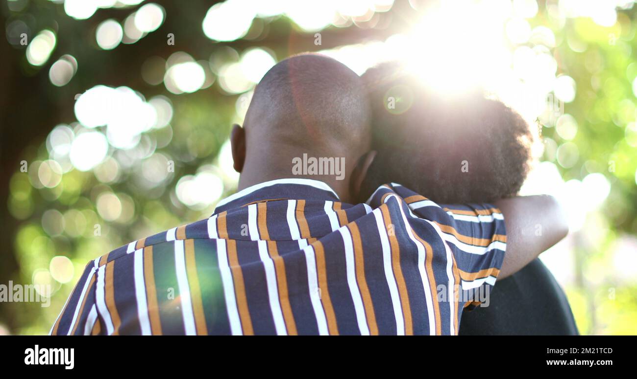 Back of African couple embracing outside in sunlight. Husband hugs wife ...