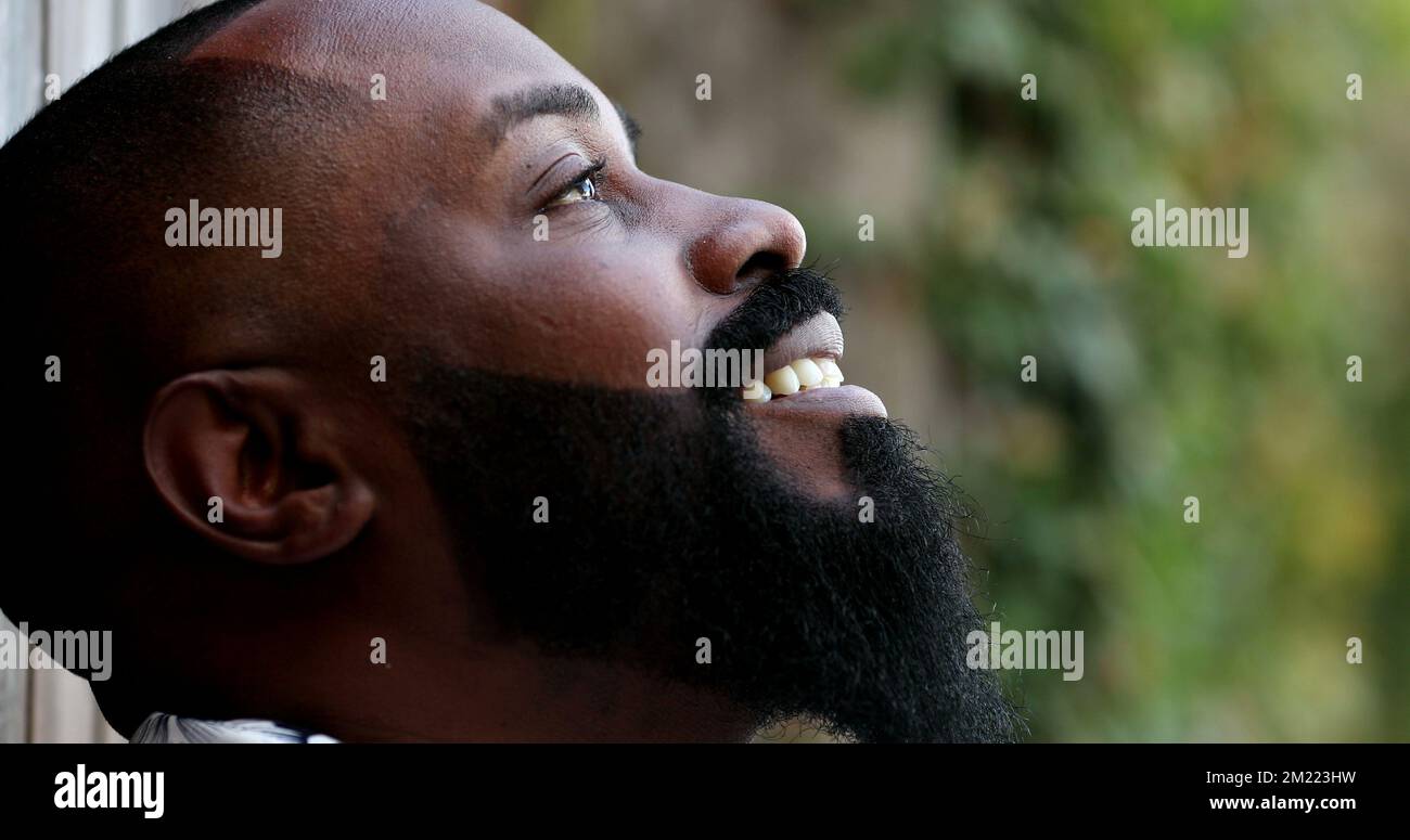 Happy optimistic black African man smiling looking at sky with HOPE and ...