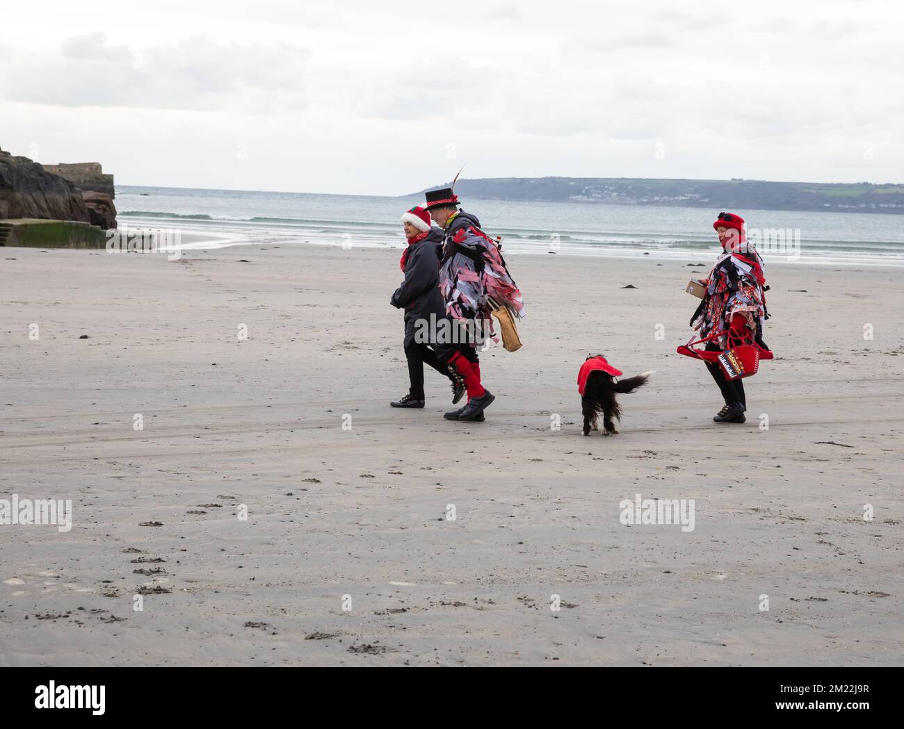 Morris Dancers walk their dog along the beach near Saint Michael's ...
