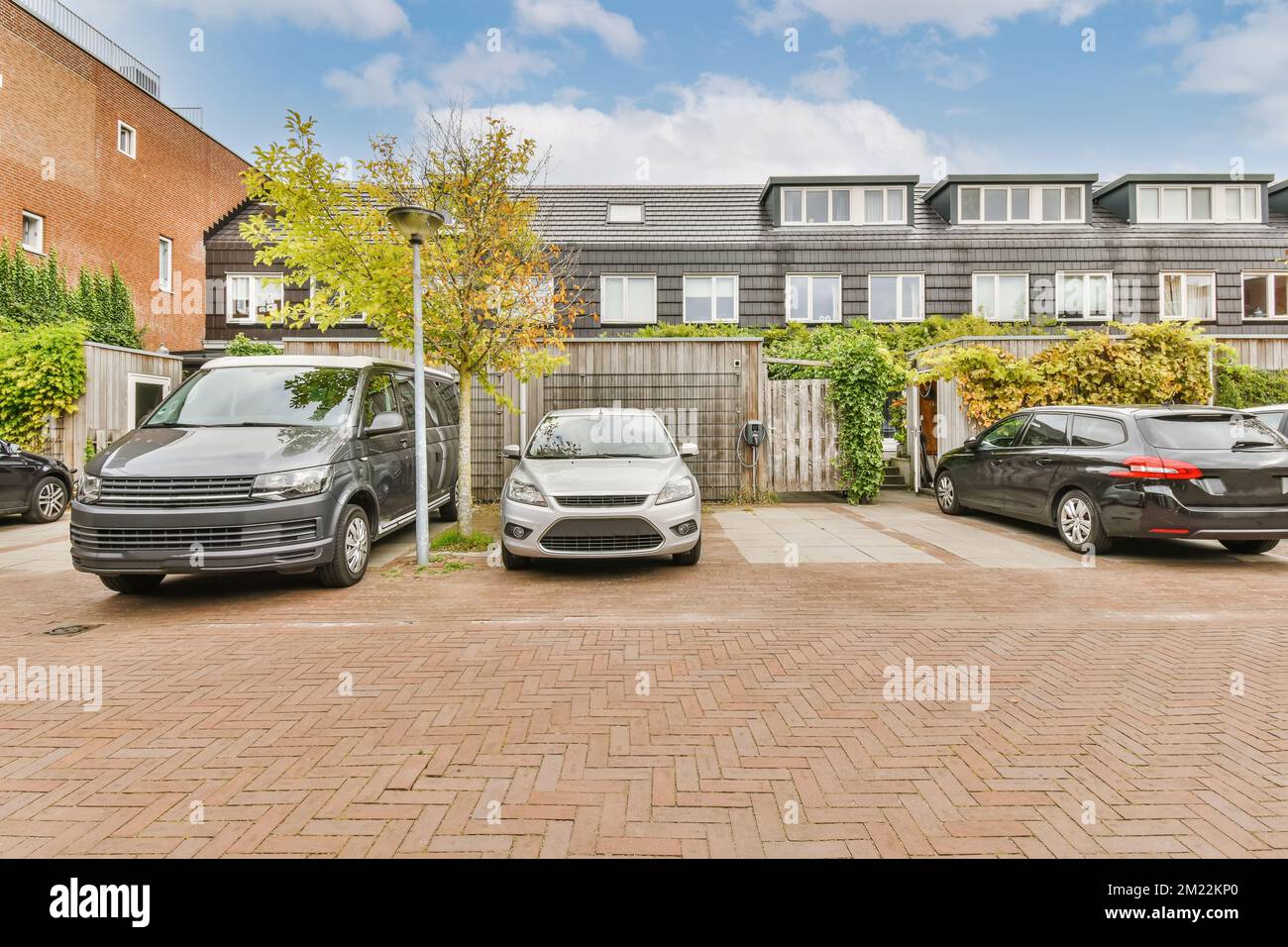 two cars parked in front of a house with blue sky and white clouds ...