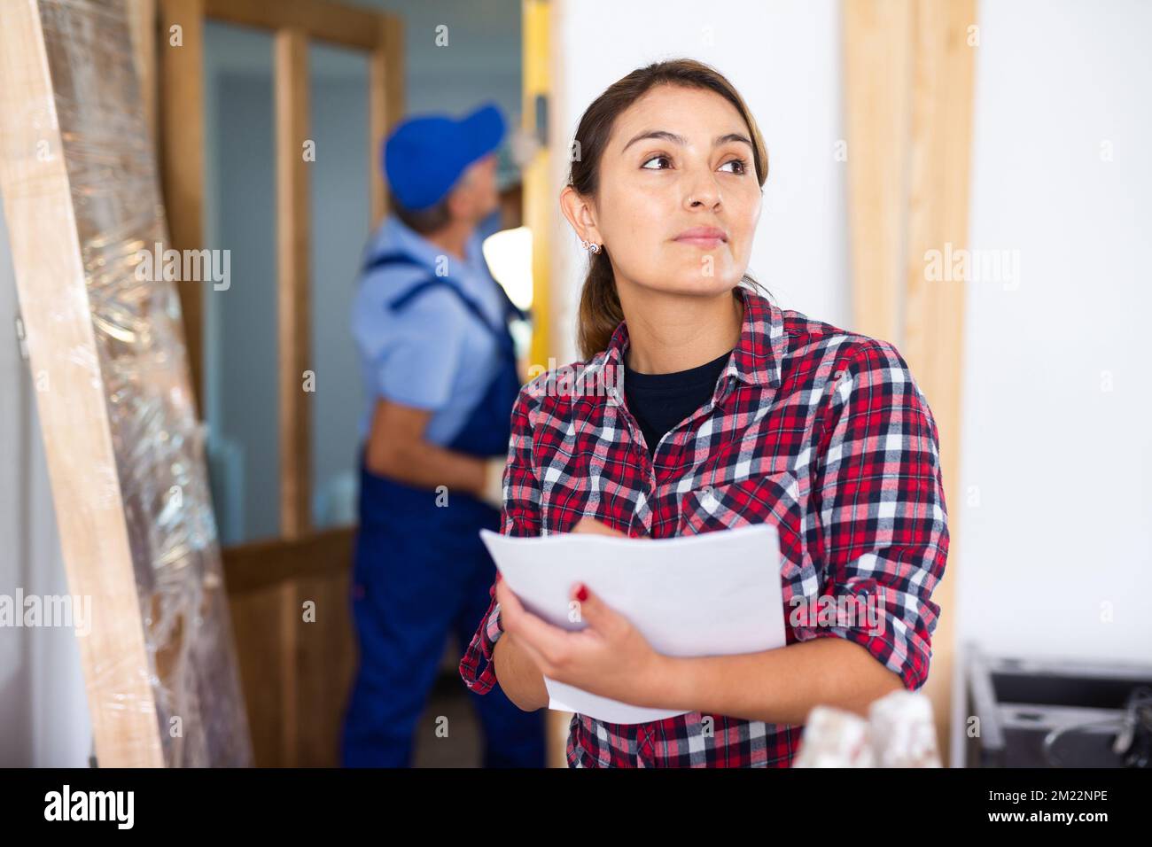 Woman inspecting rooms in building site, checking documents Stock Photo ...