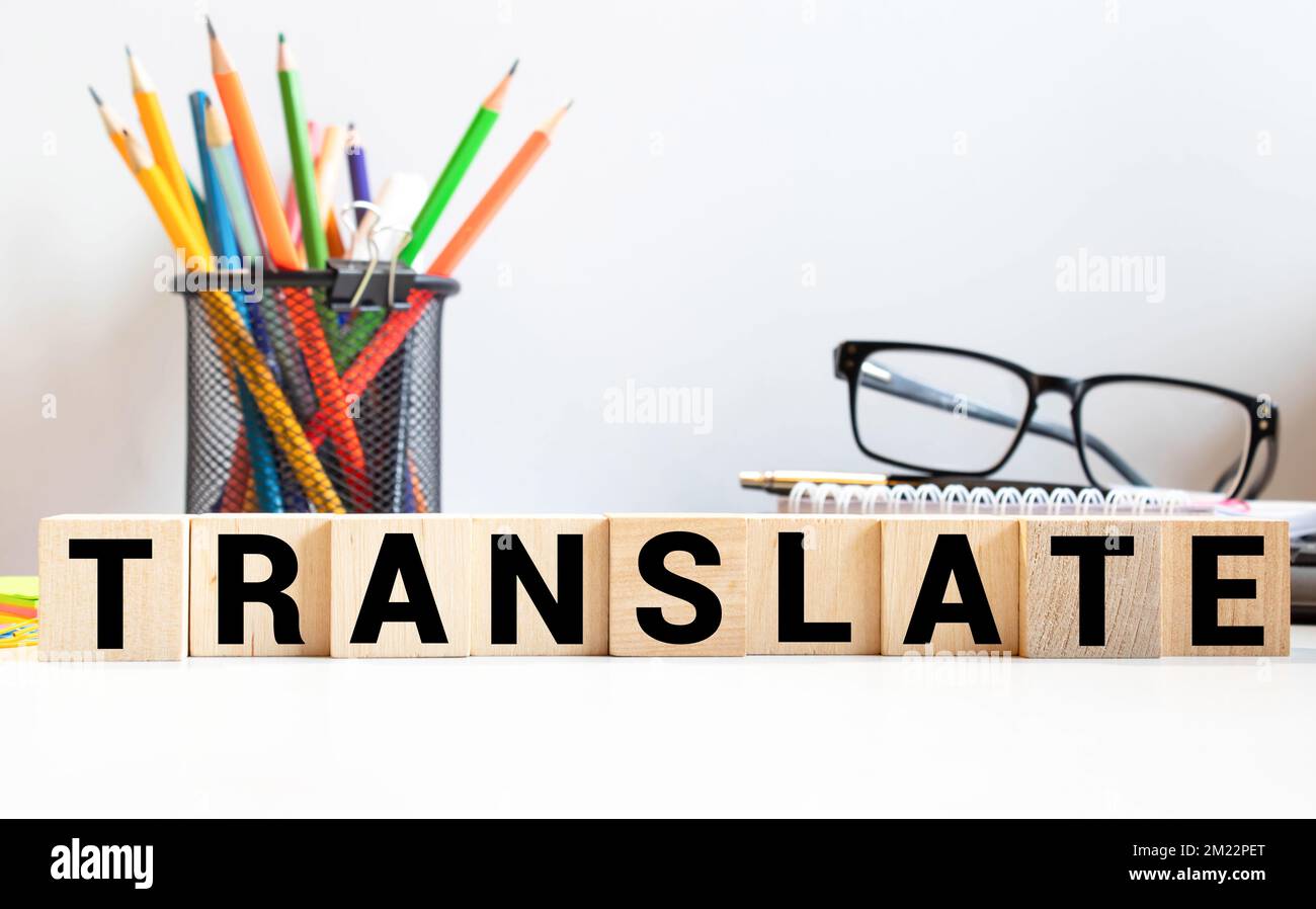 Woman making word Translate with wooden cubes at white table, top view ...
