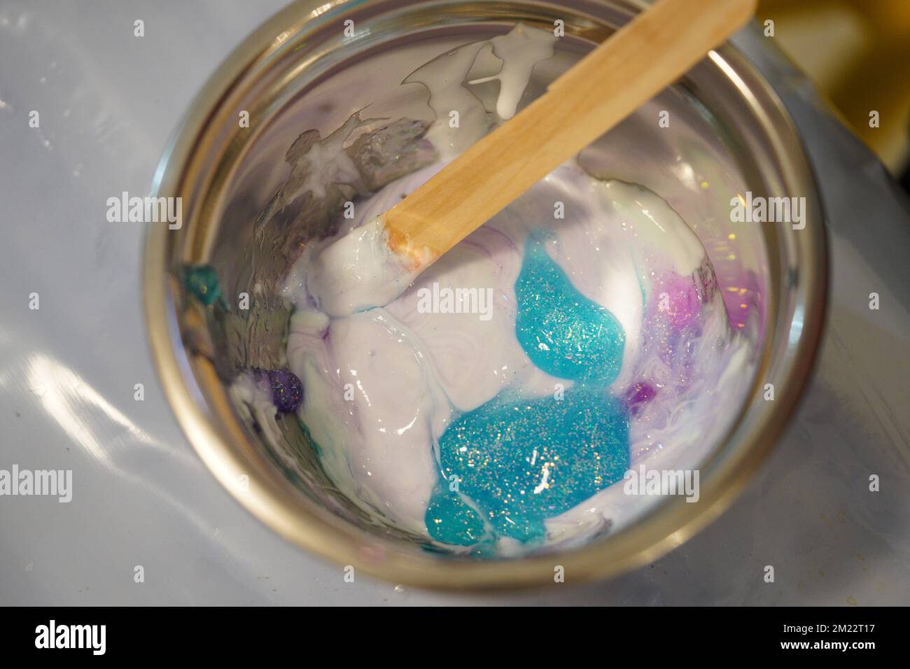 kid making slime adding glitter glue and white glue mixing it with ...