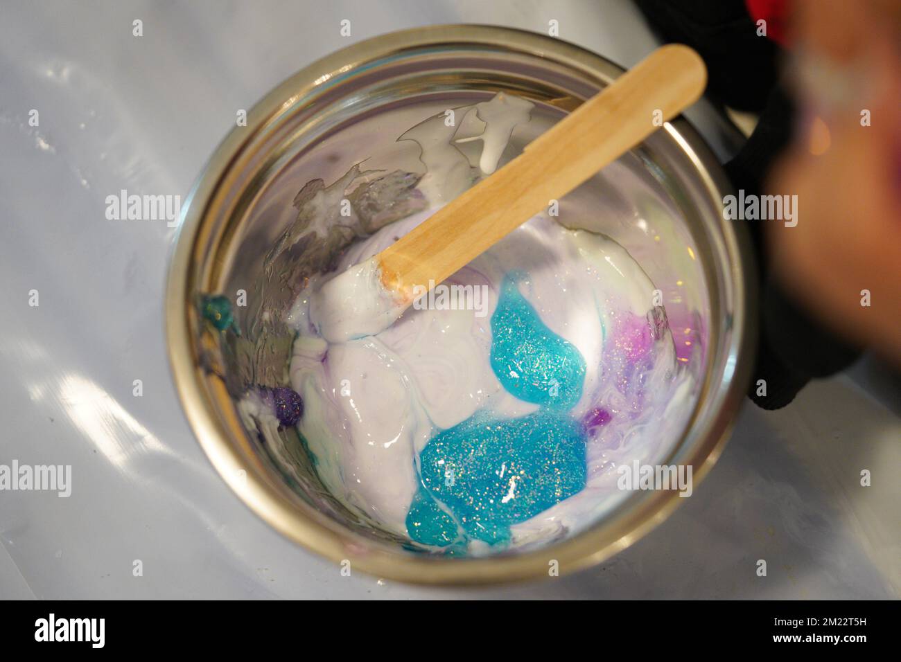 kid making slime adding glitter glue and white glue mixing it with ...