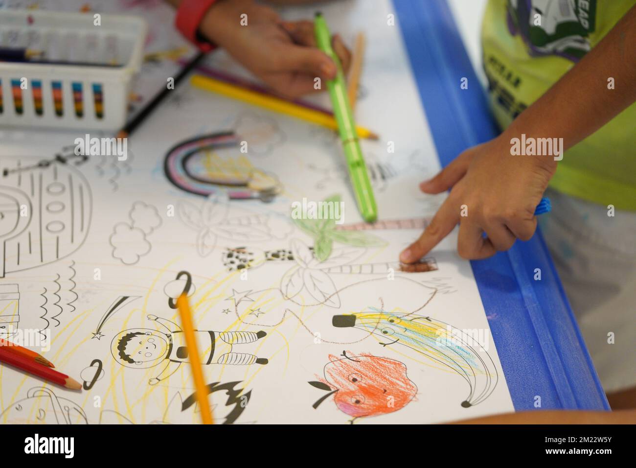 A child sits and colours a giant colouring paper pattern. Child holds a ...