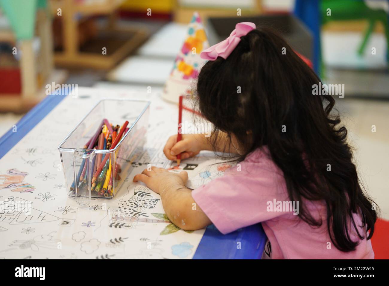 A child sits and colours a giant colouring paper pattern. Child holds a ...