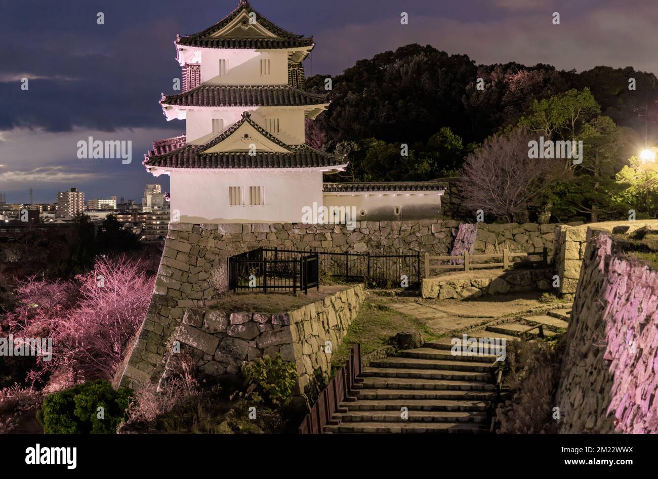 Watchtower atop stone castle walls in Japanese park as night falls ...