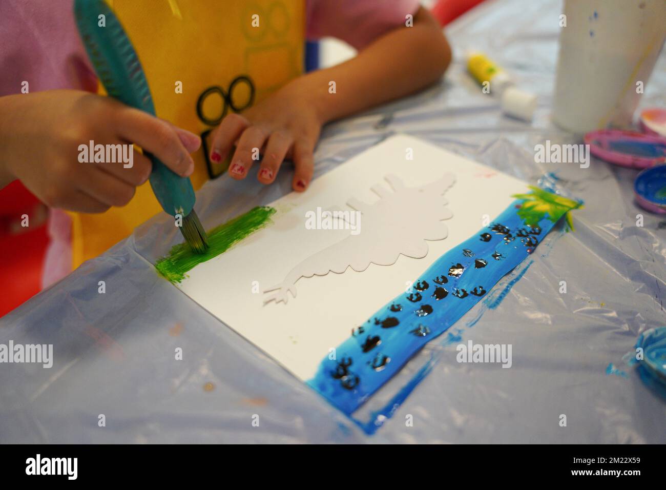 A child is painting a discourse's paints with a brush and wearing an ...