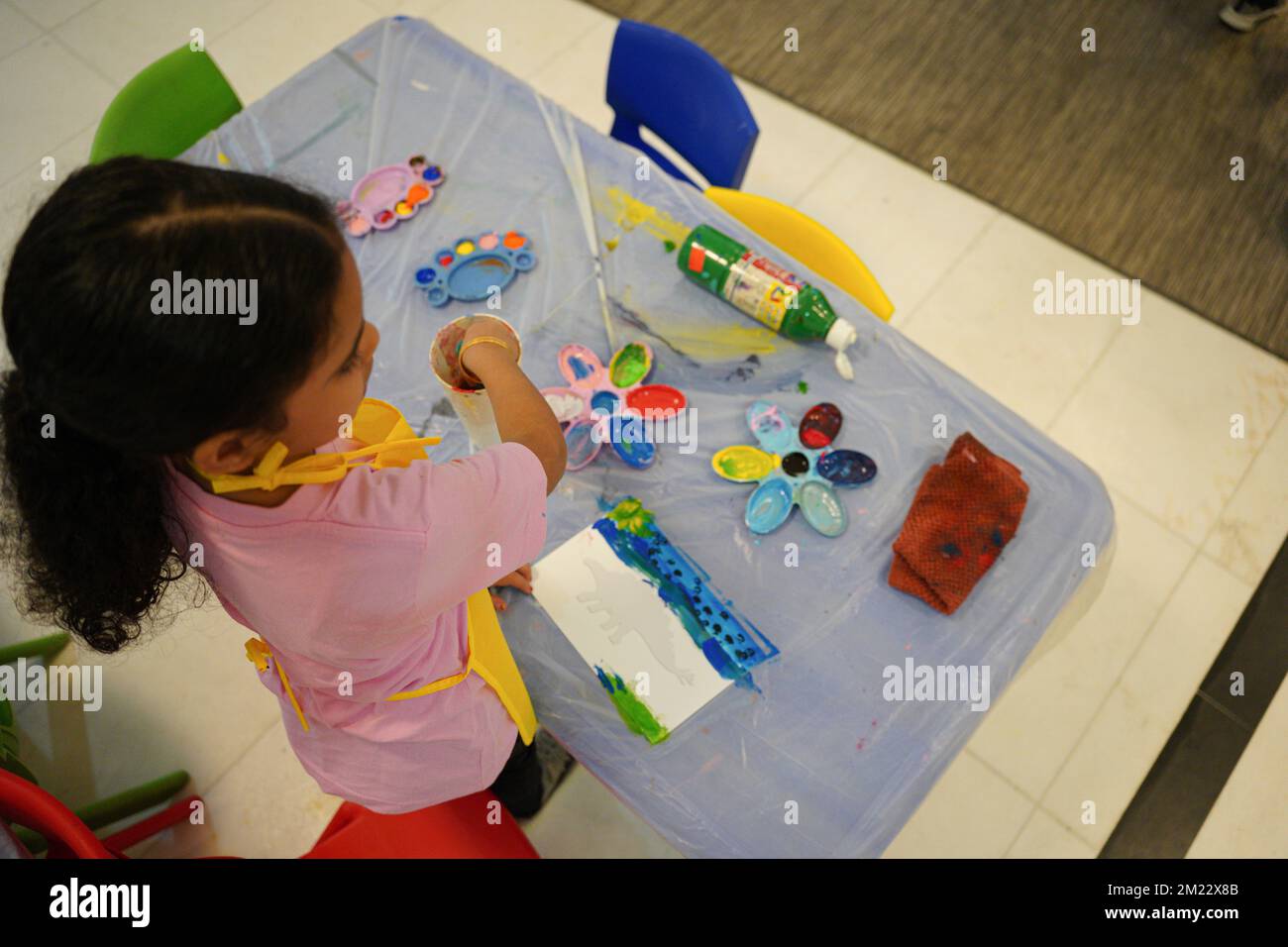 Little girl painting with colourful paints using brushes and colour ...