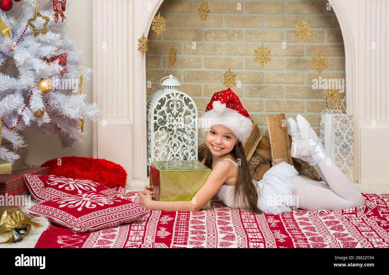 Little girl in fairy pixi costume dress with Santa hat is posing beside ...