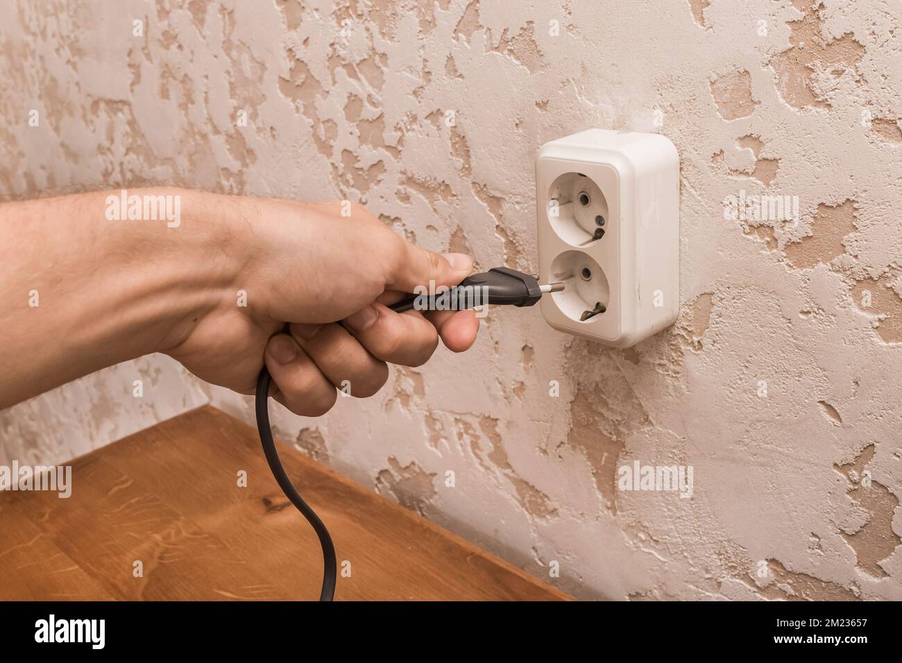 A man hand inserts or removes a plug from an outlet in a modern ...