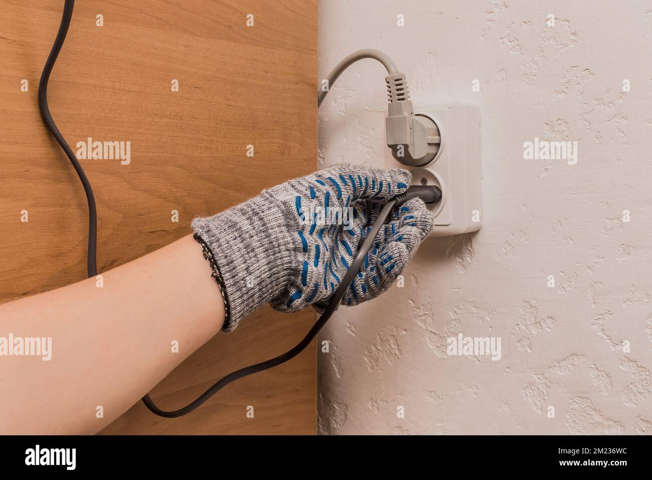 The hand of a male construction worker in protective gloves connects a ...