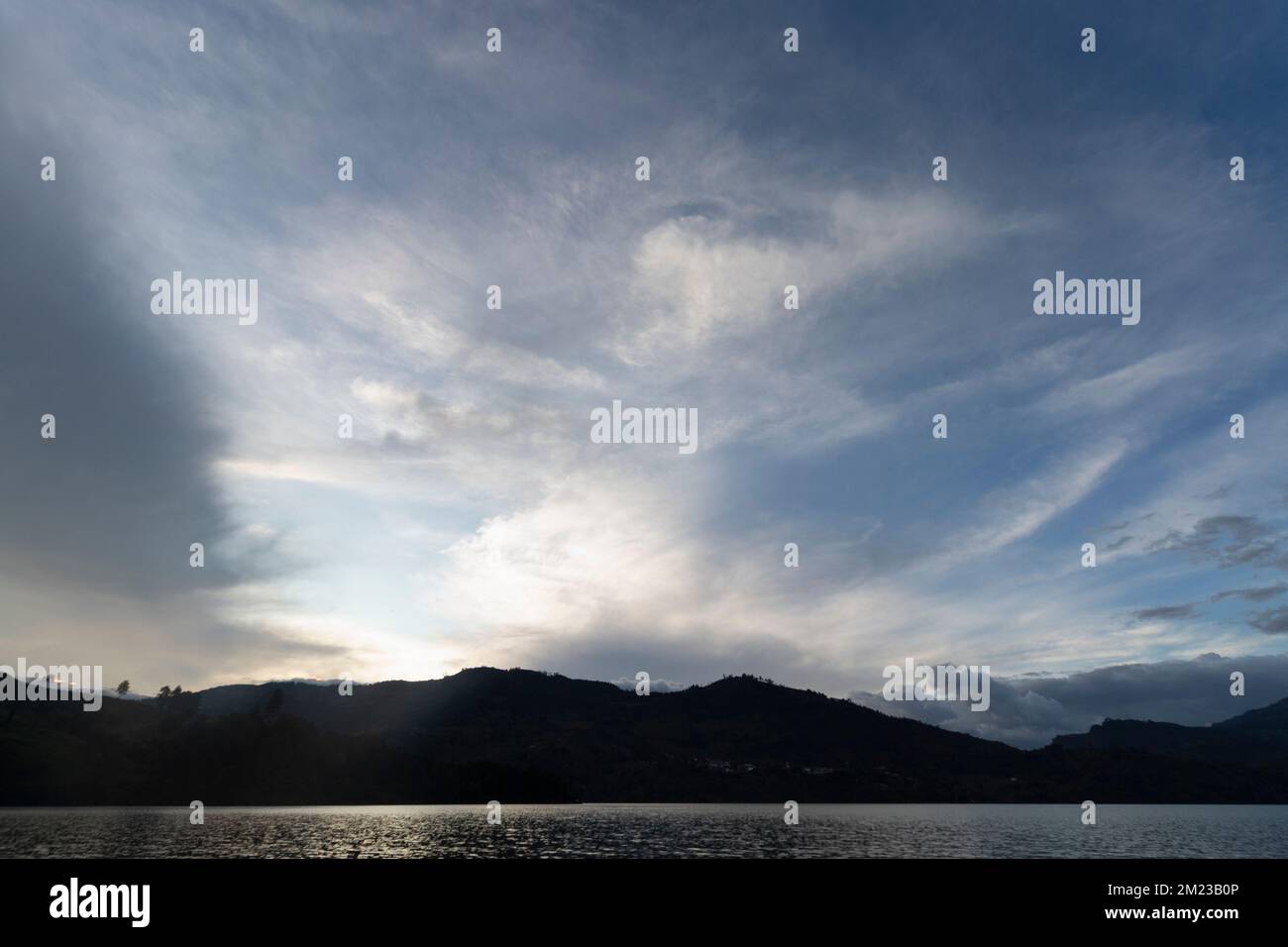 Beautiful sunset skyscape with mountain range silhouette and lake water ...