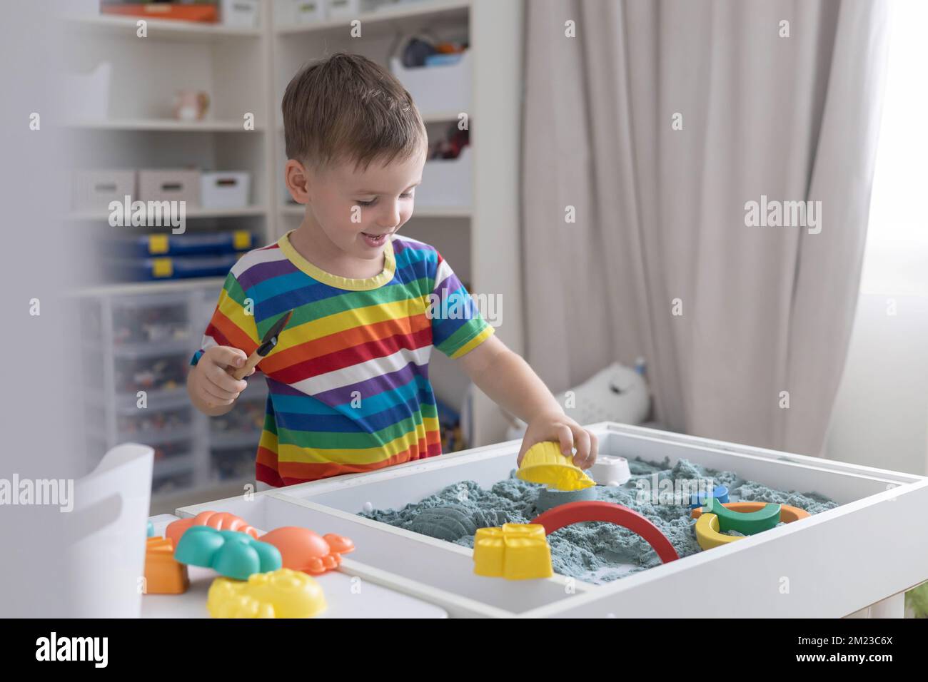 Overjoyed male kid playing kinetic sand early development education ...