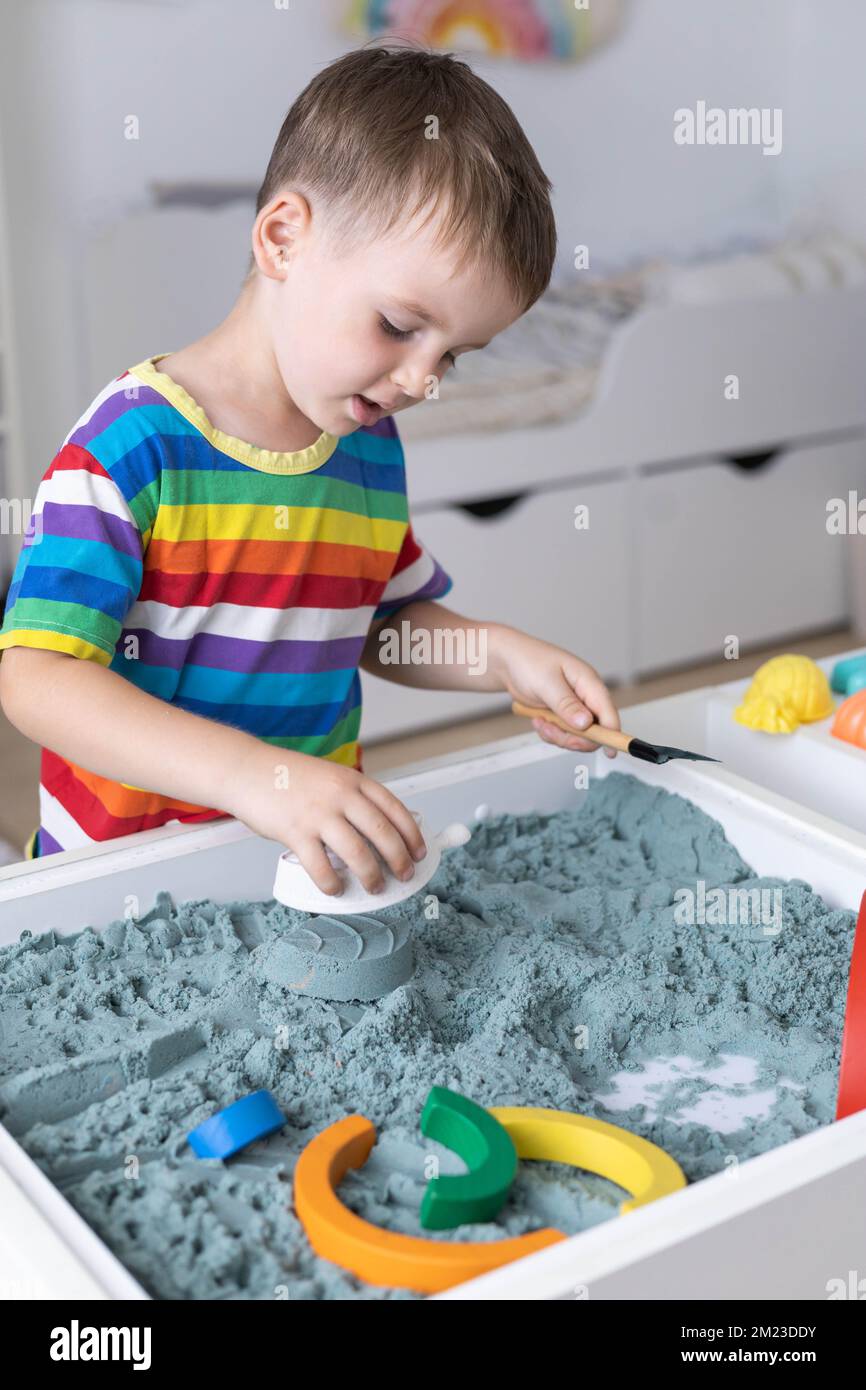 Overjoyed male kid playing kinetic sand early development education ...