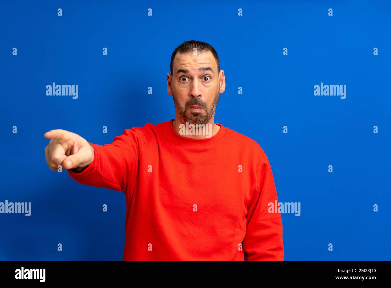 Bearded latino man in a red pullover pointing finger at the camera ...