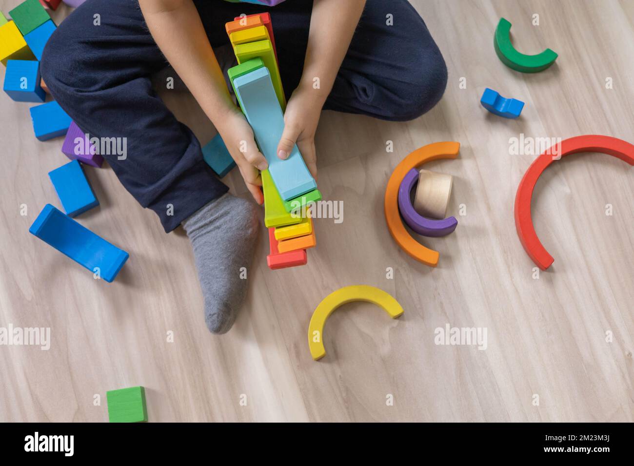 Child boy playing colored rainbow wooden Montessori material arch ...