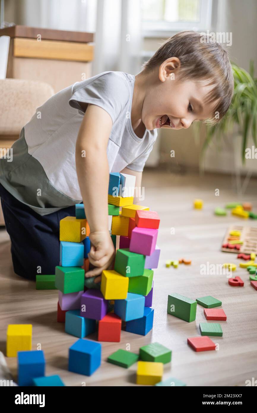 Confident male kid building fortress tower architecture wooden bricks ...