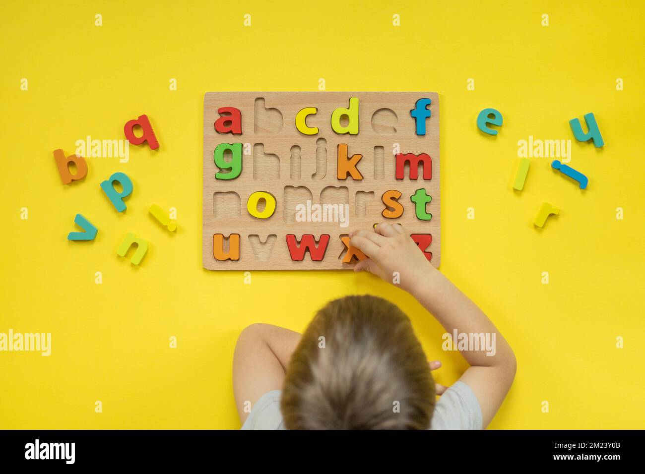 Childish hands holding alphabet wooden board with colored font letters ...