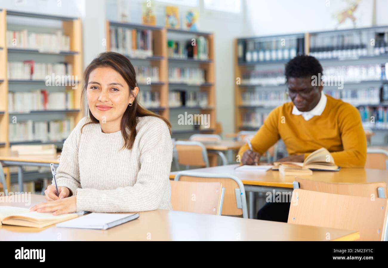 Young adult woman studying in public library Stock Photo - Alamy