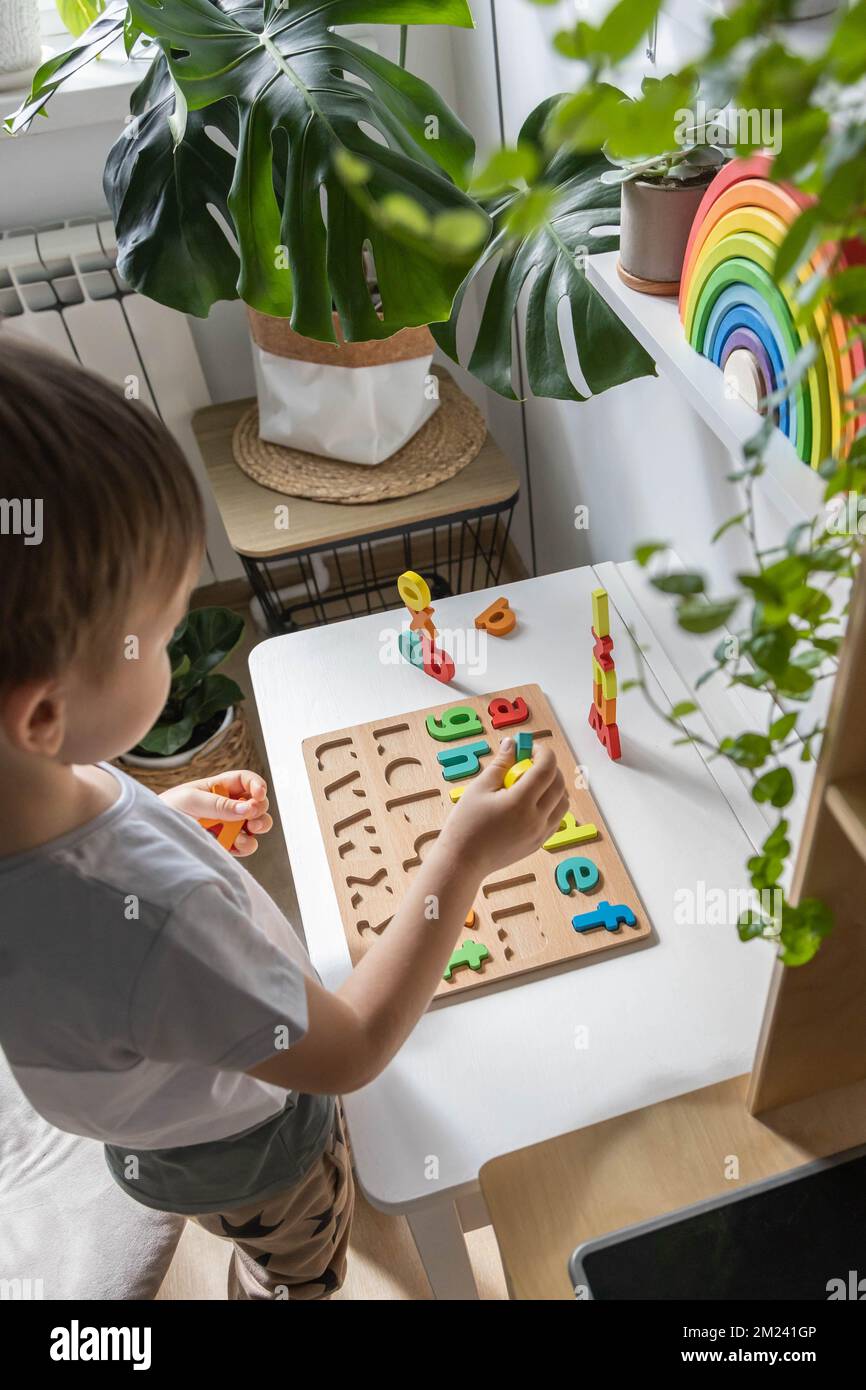 Boy kid assembling flat letters wooden puzzle block cell playing ...