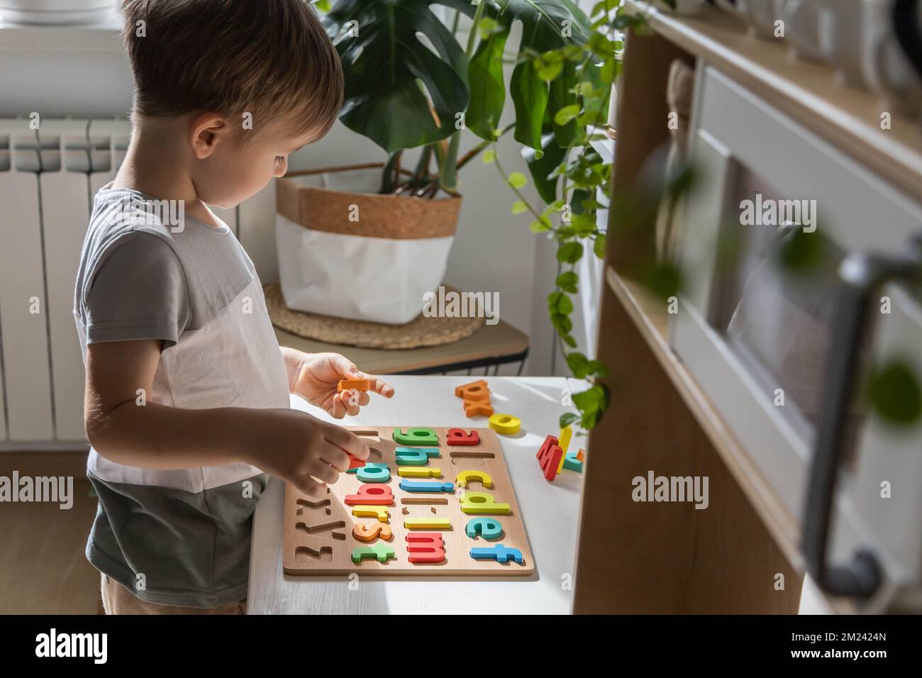 Boy kid assembling flat letters wooden puzzle block cell playing ...