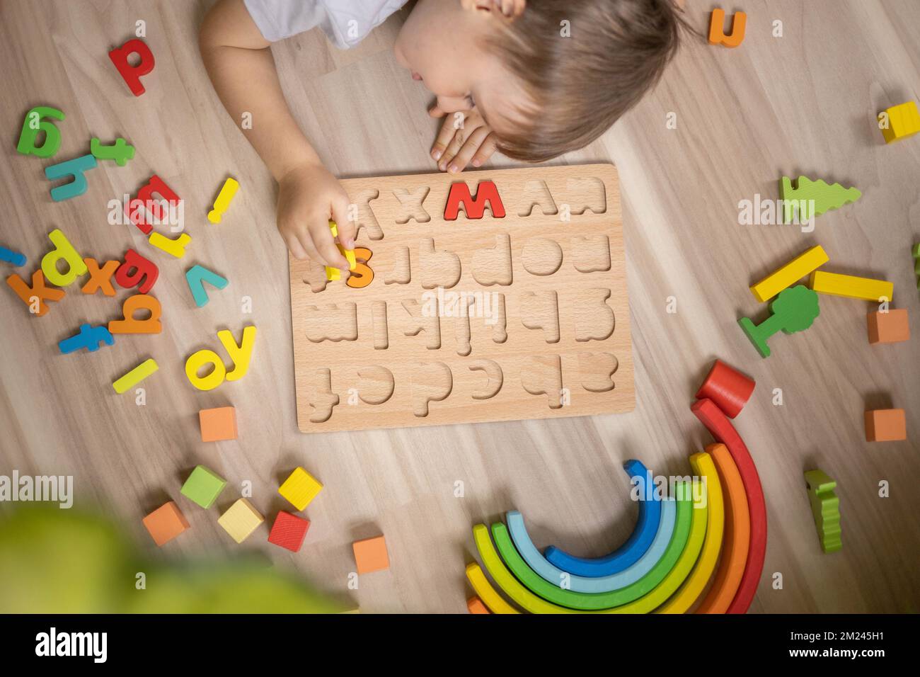 Male kid playing with wooden eco friendly alphabet letters board on ...