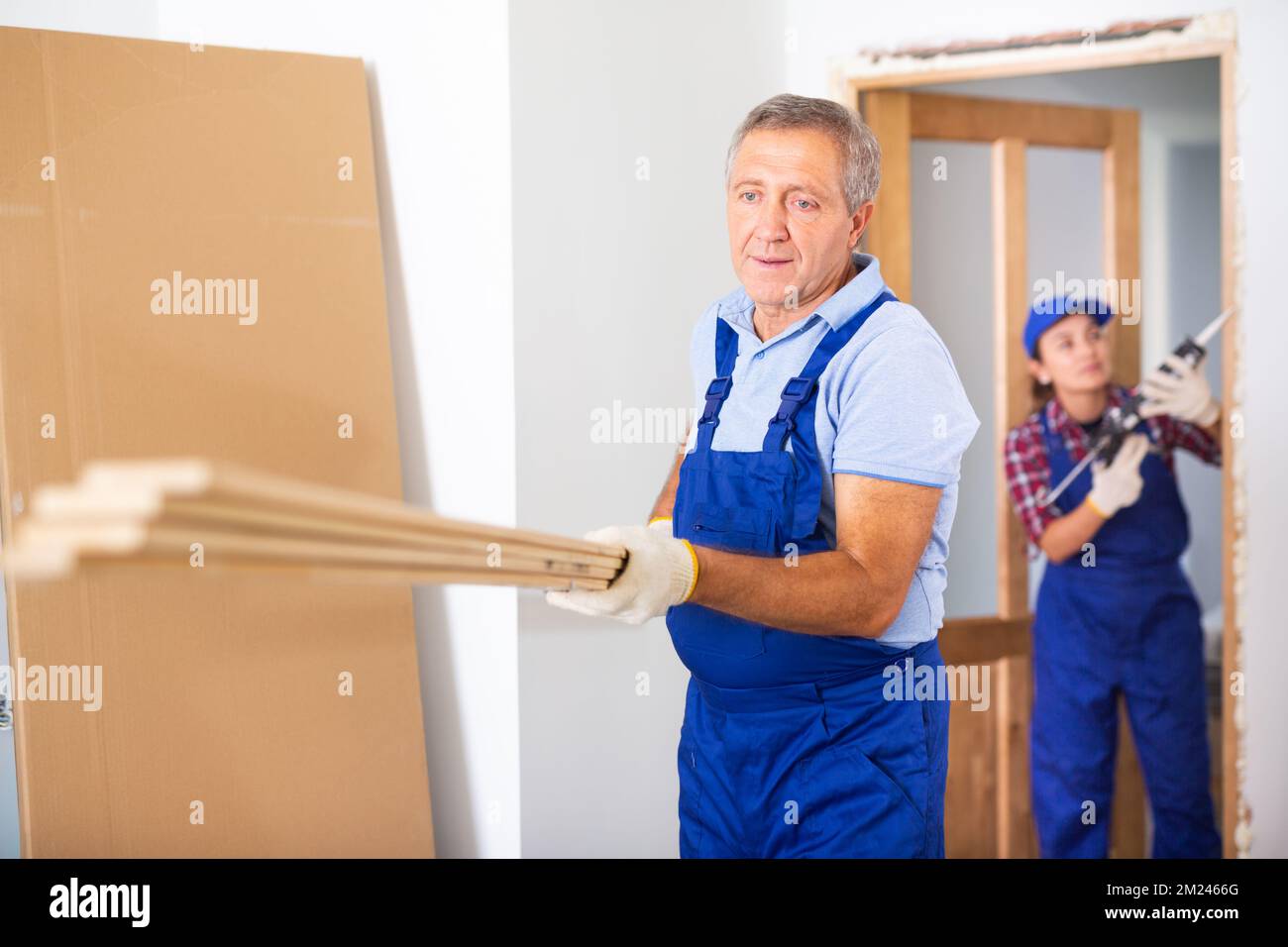 Man builder carrying wooden planks in construction site Stock Photo - Alamy