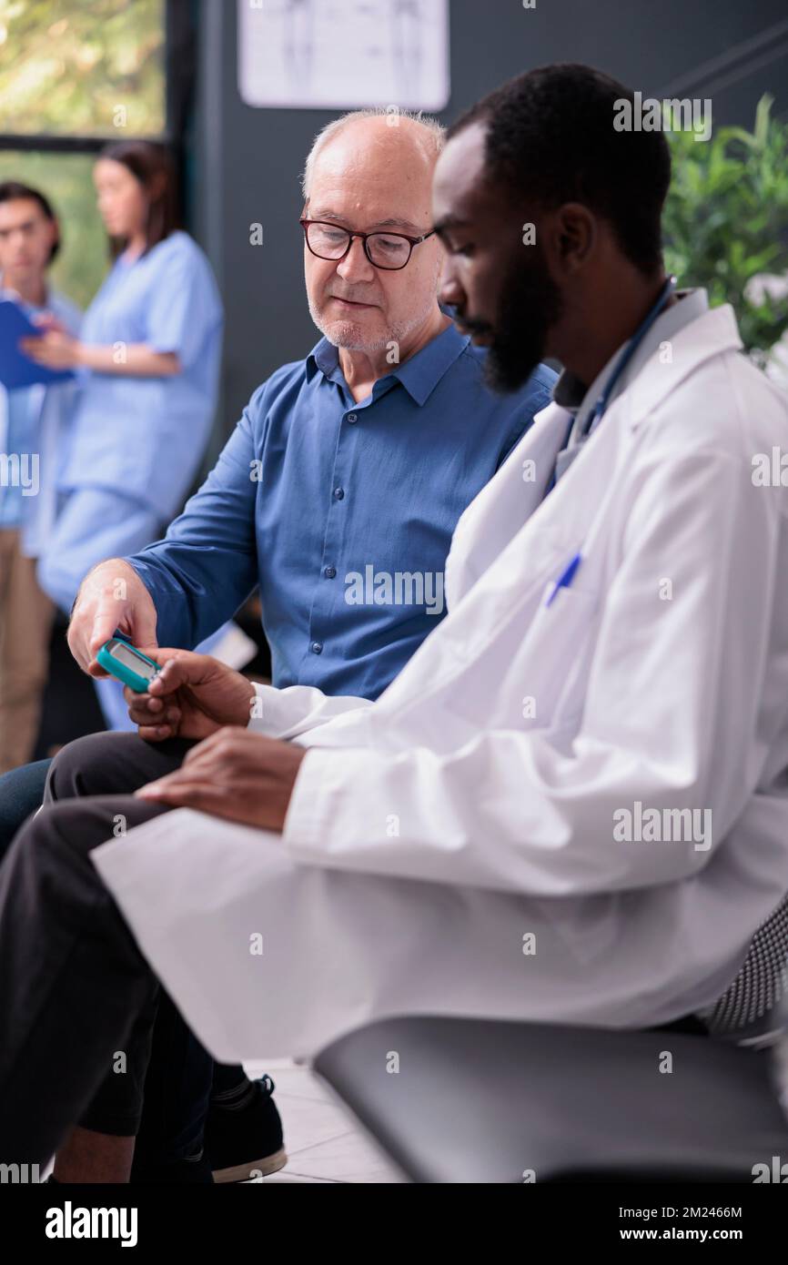 African american medic consulting senior patient with glucometer ...