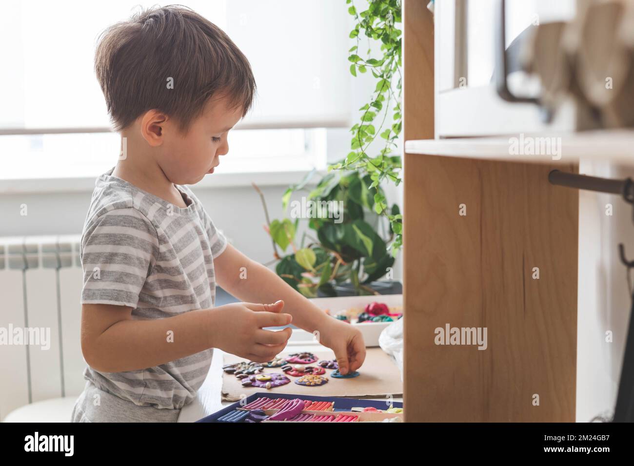 Baby boy creating plasticine diy figure with decorate dried beans ...
