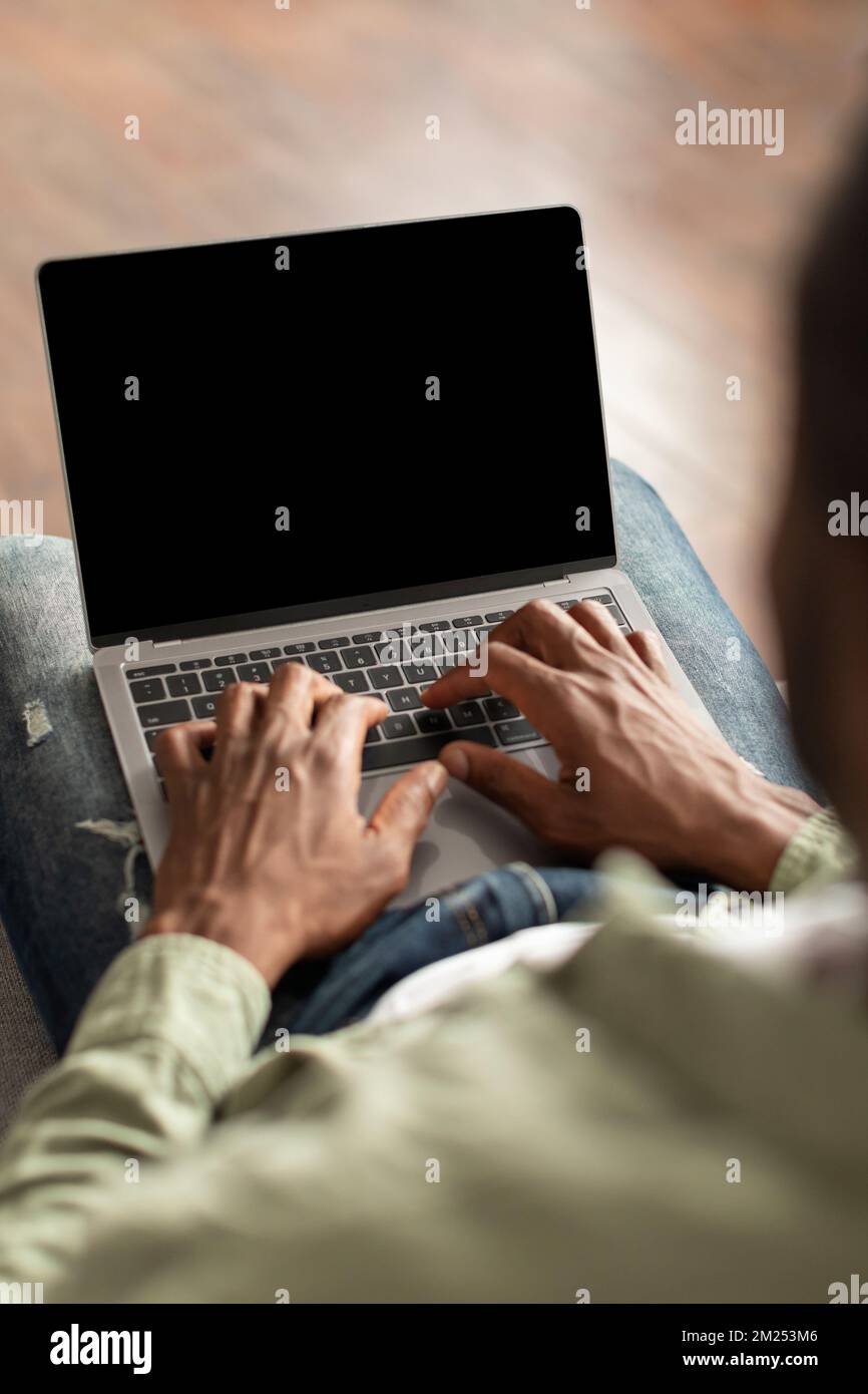 Mature black guy typing on computer keyboard with blank screen ...