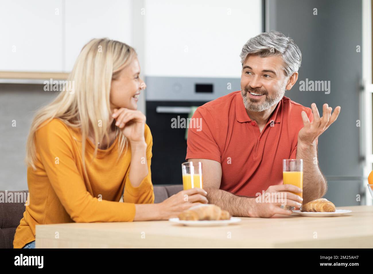 Happy loving couple having conversation while eating at kitchen Stock ...
