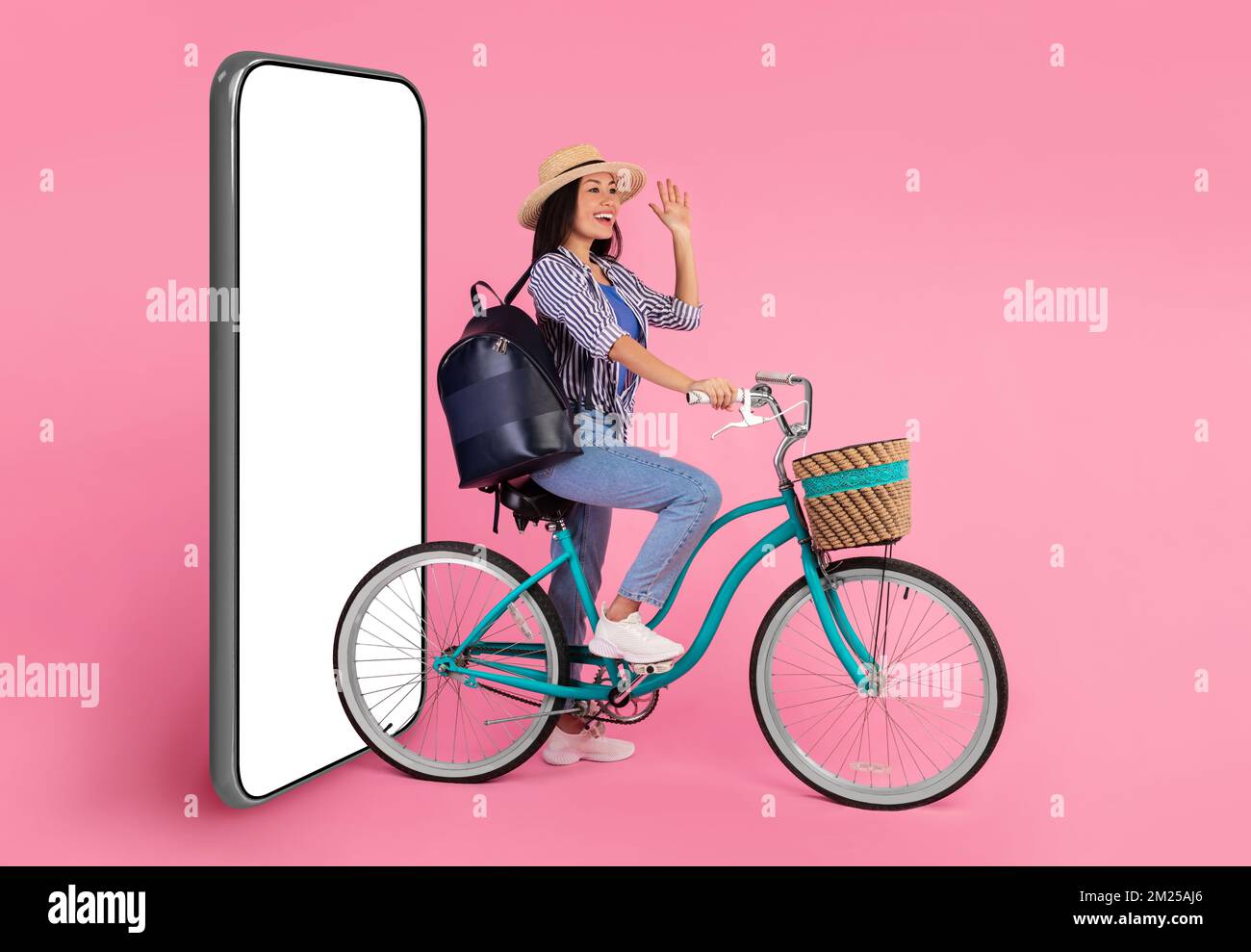 Excited asian woman riding bicycle waving hand, smartphone with mockup ...