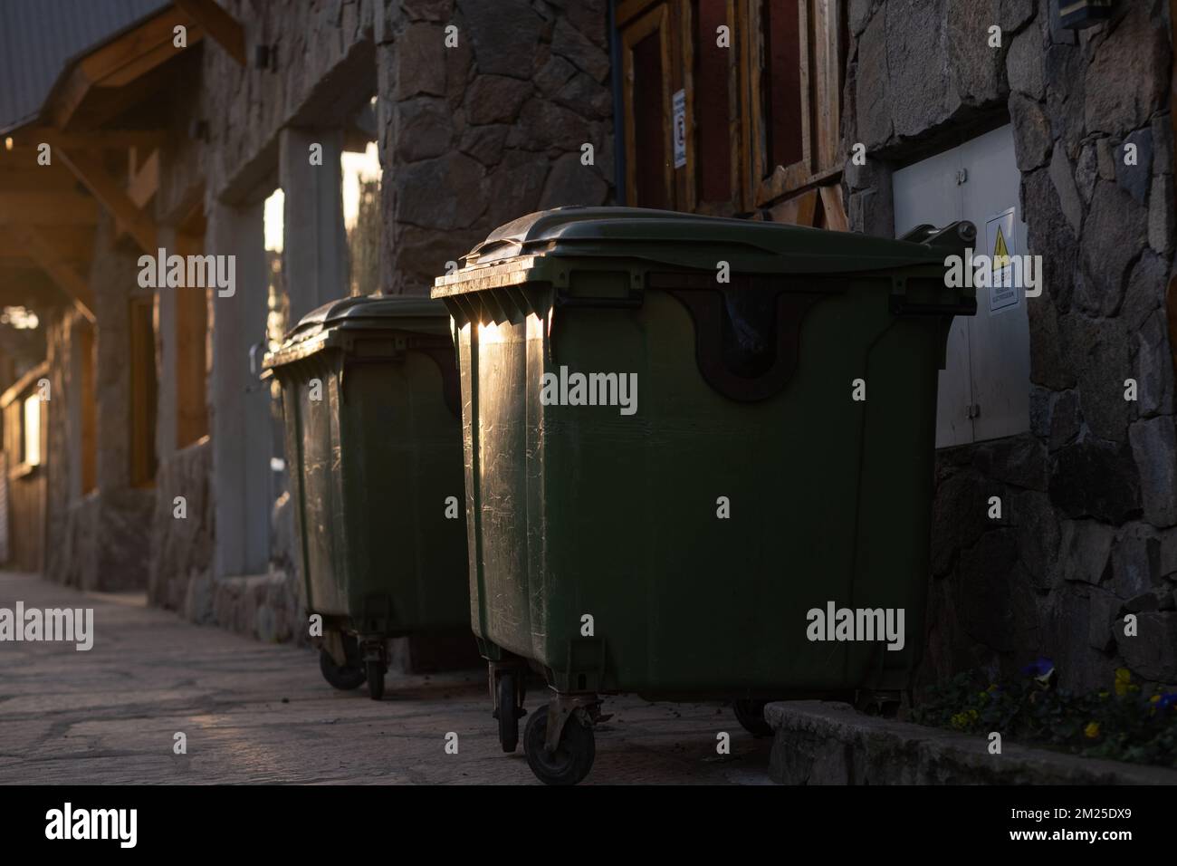 A view of green garbage bins on the street during sunrise Stock Photo ...