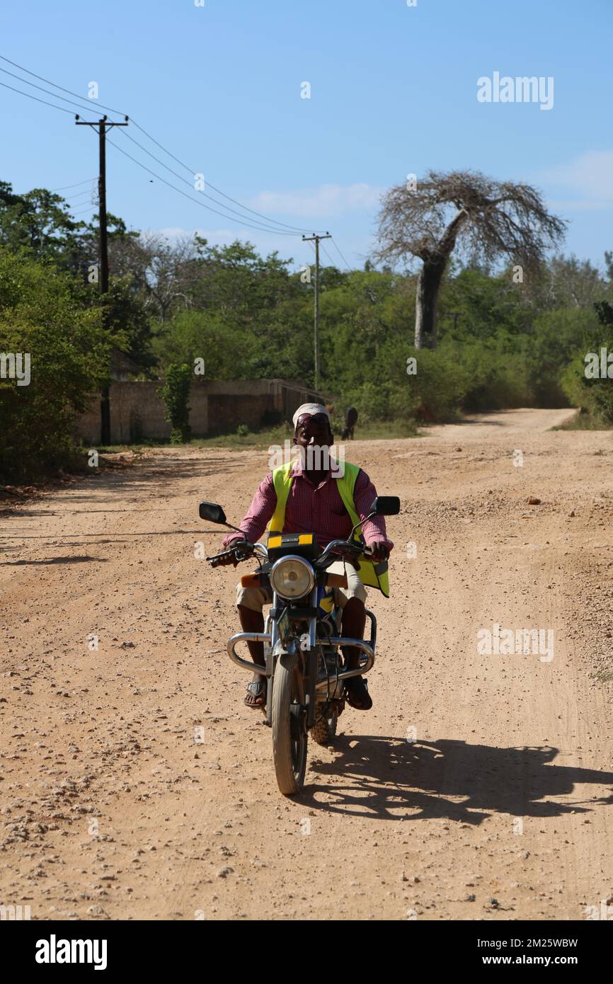A vertical shot of African man on a bike on a dirt road in Ukunda ...