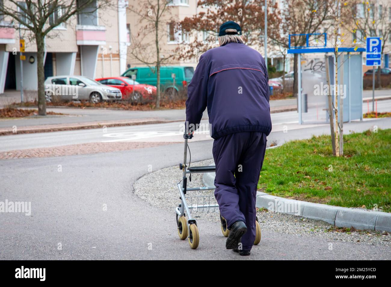 An elderly man walking with a wheeled walker on an empty street in ...