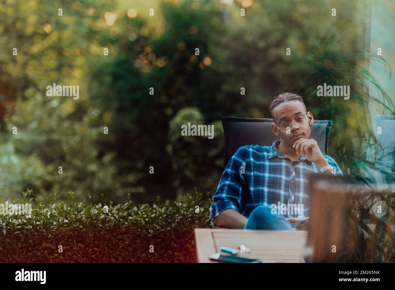An African American man sitting in front of the house on a modern ...