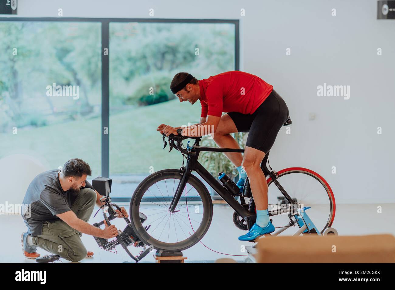 A cameraman filming an athlete riding a triathlon bike on a simulation ...