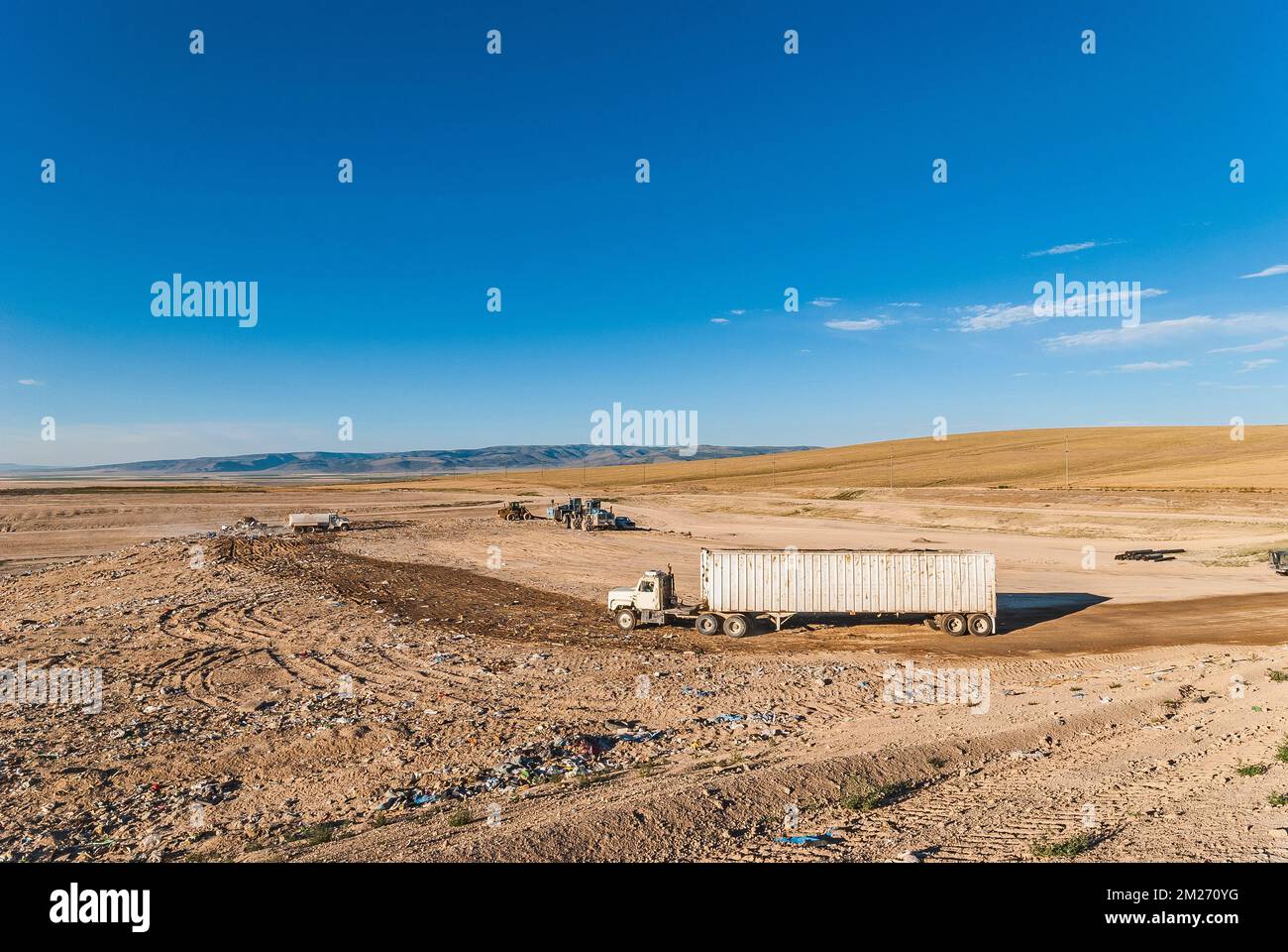 Three soil compactors and a watering truck on flat land in an active ...