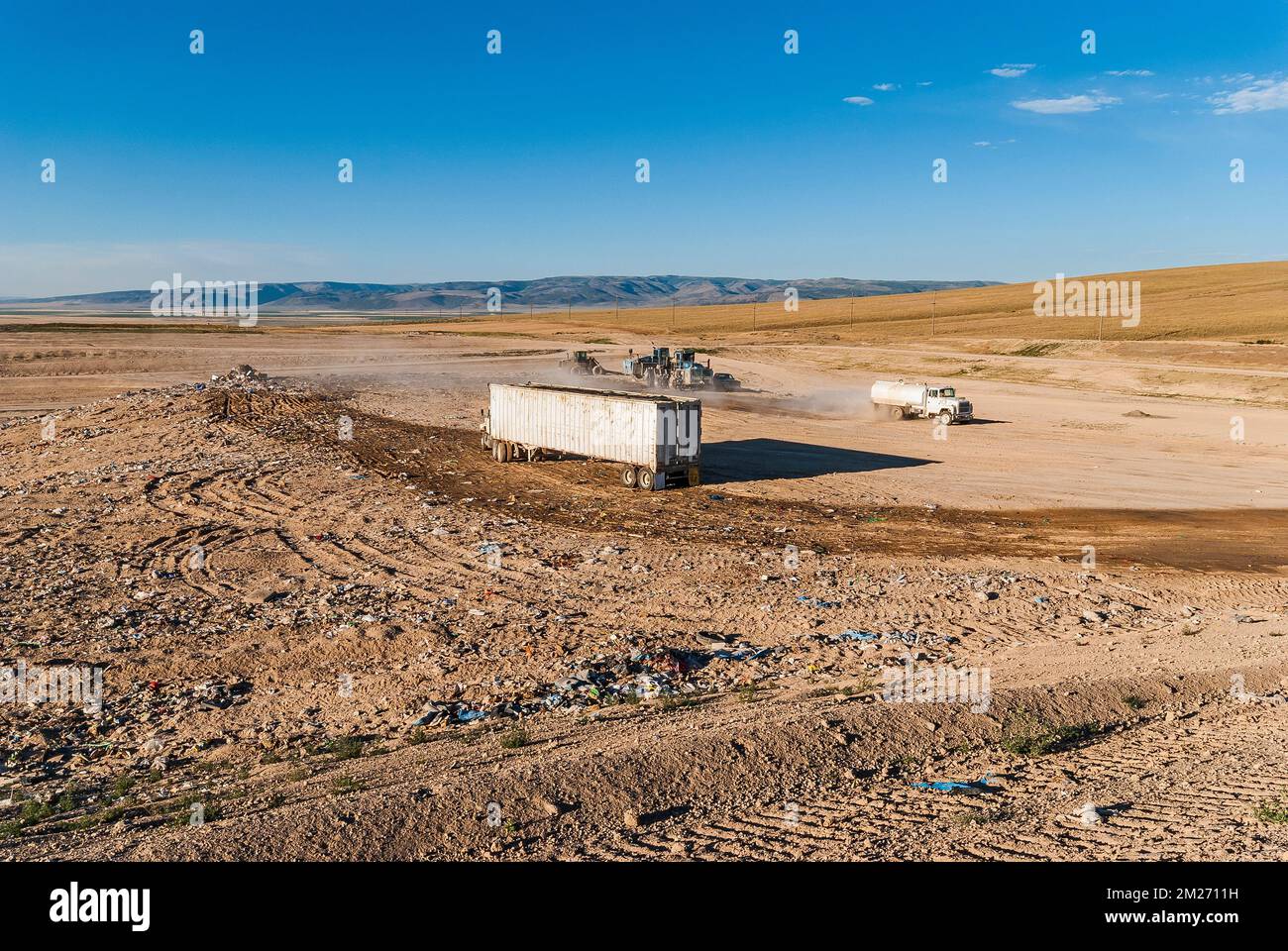 Three soil compactors and a watering truck on flat land in an active ...