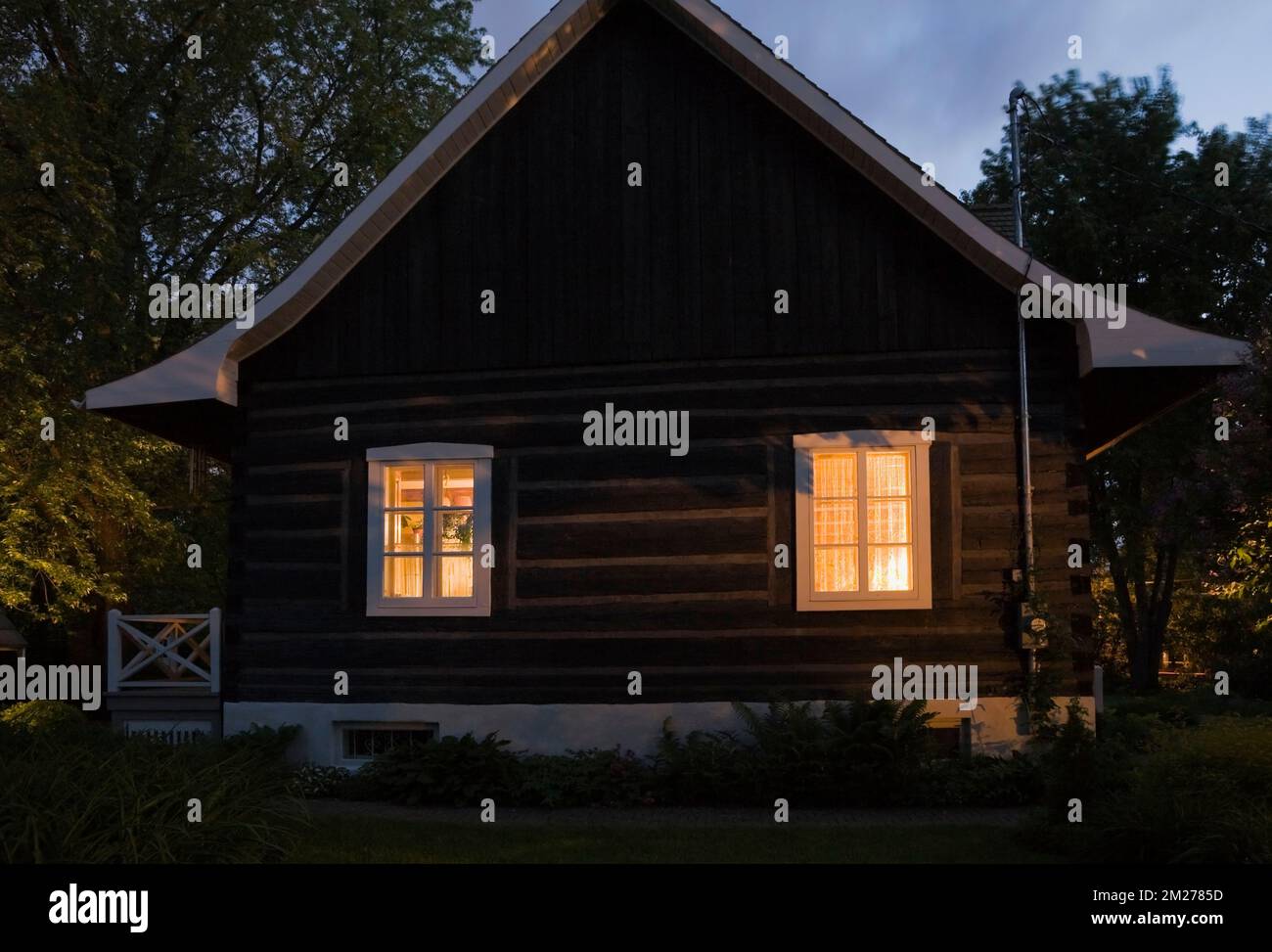 Side view of old style log home illuminated at dusk Stock Photo - Alamy