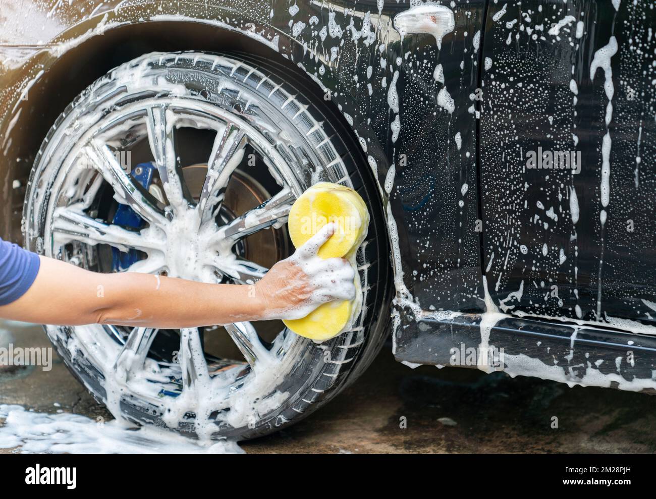 Car service washing car wheels with yellow sponge at outdoor. Car ...