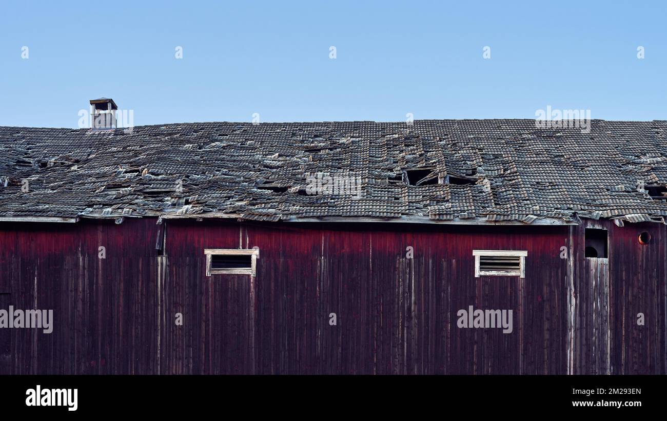 A shabby, reddish building with a metal roof that has holes in it Stock ...