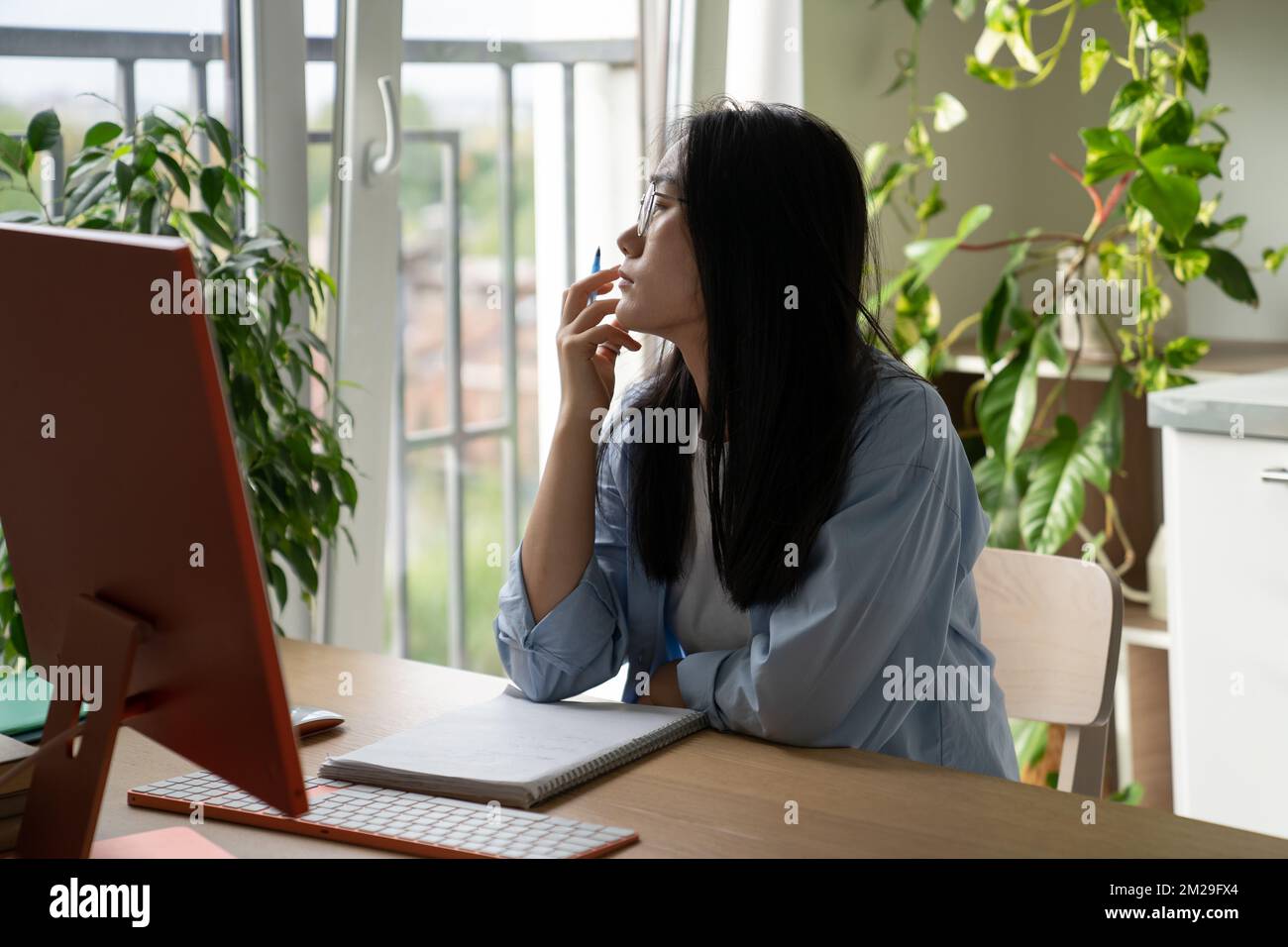 Dreamy pensive Asian student girl looking out window while studying ...