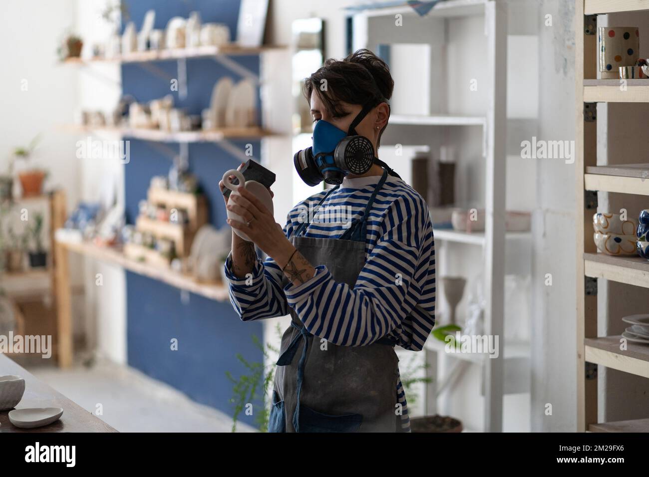 Italian female ceramic artist polishing pottery in studio, smoothing ...