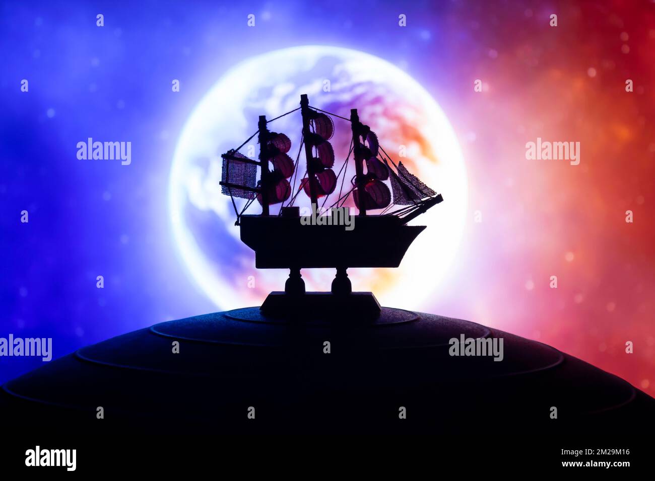 Beautiful boat toy over a blue balll with blurred blue and red planet ...