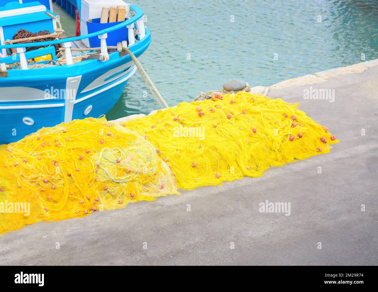 Yellow fishing nets on the pavement next to the boat Stock Photo - Alamy