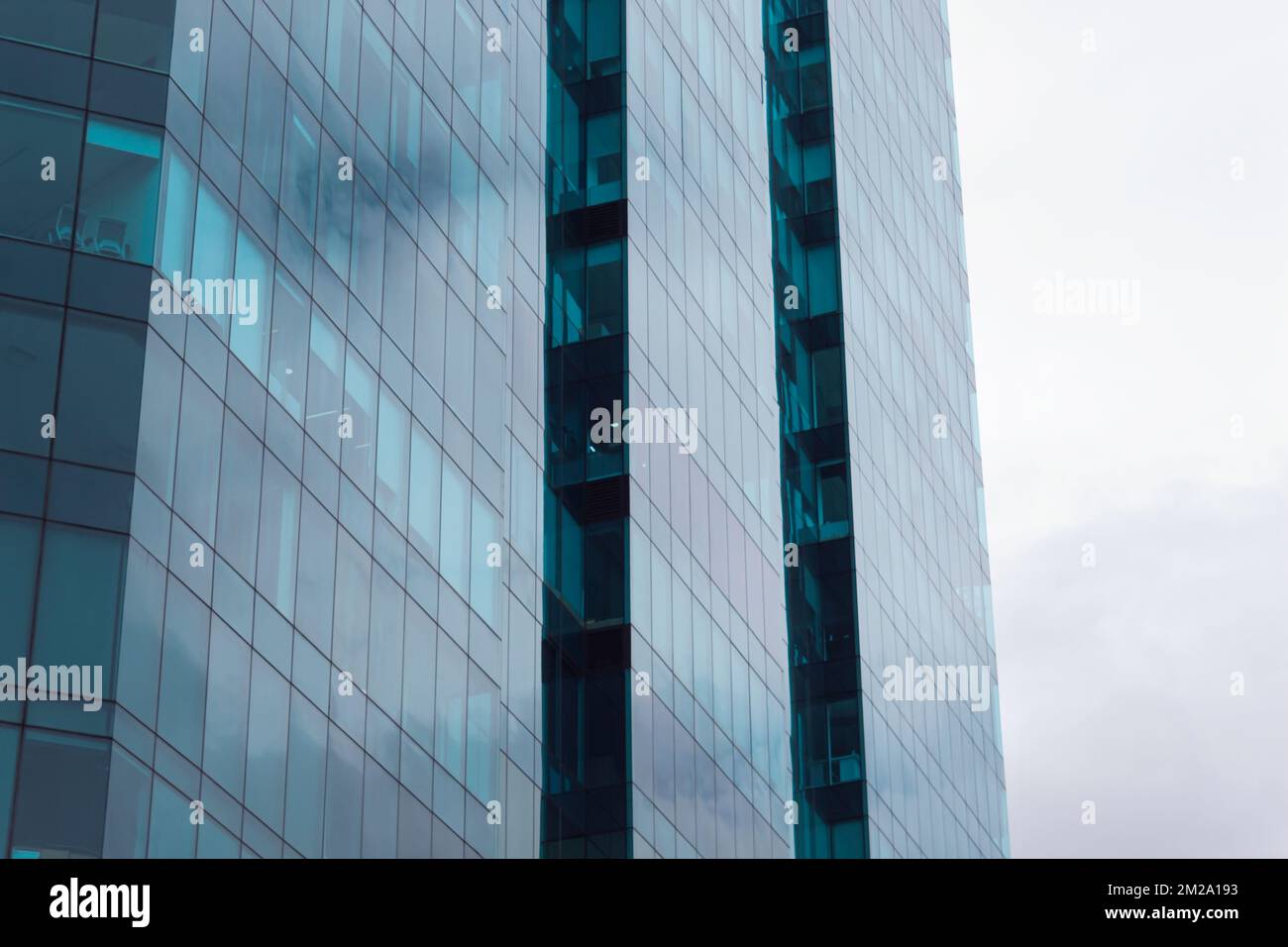 closeup to a modern blue skyscraper windows with blue cloudy sky behind ...