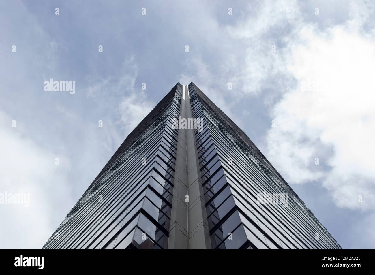 Low angle view of a modern skyscraper corner with blue cloudy sky at ...